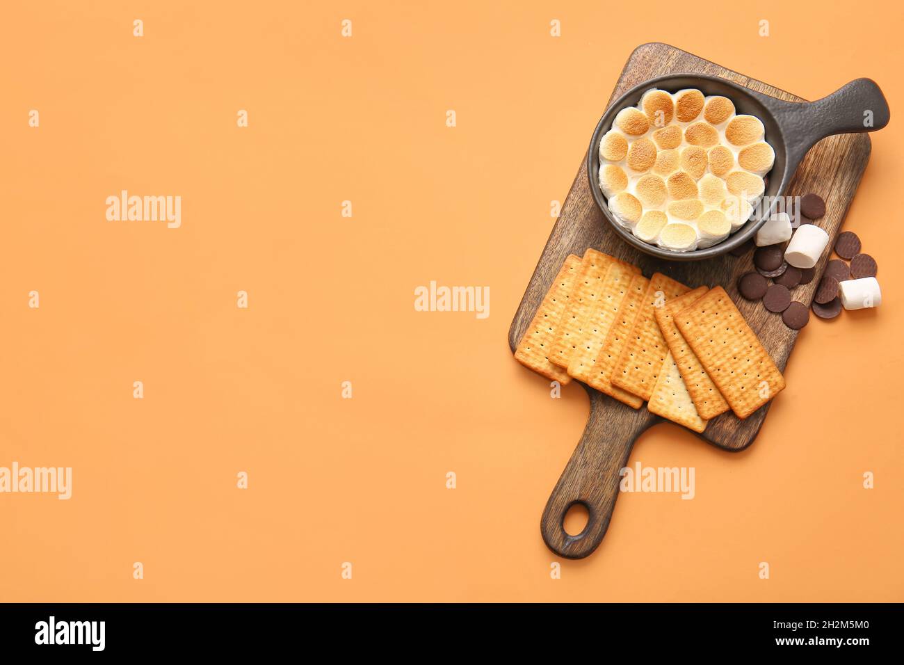 Frying pan with delicious S'mores dip and crackers on color background ...