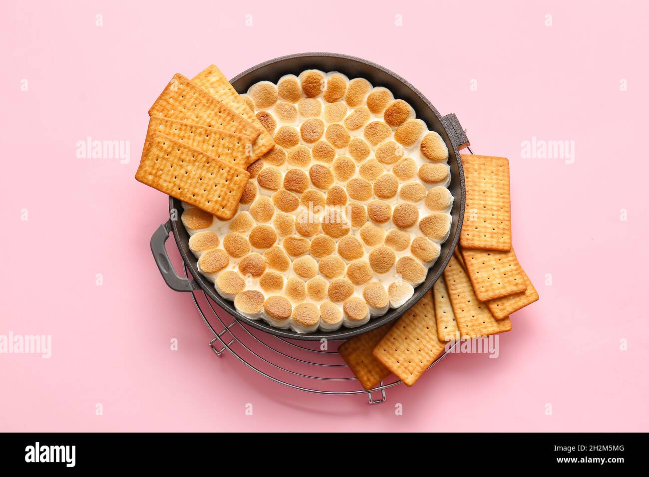 Frying pan with tasty S'mores dip and crackers on pink background Stock ...
