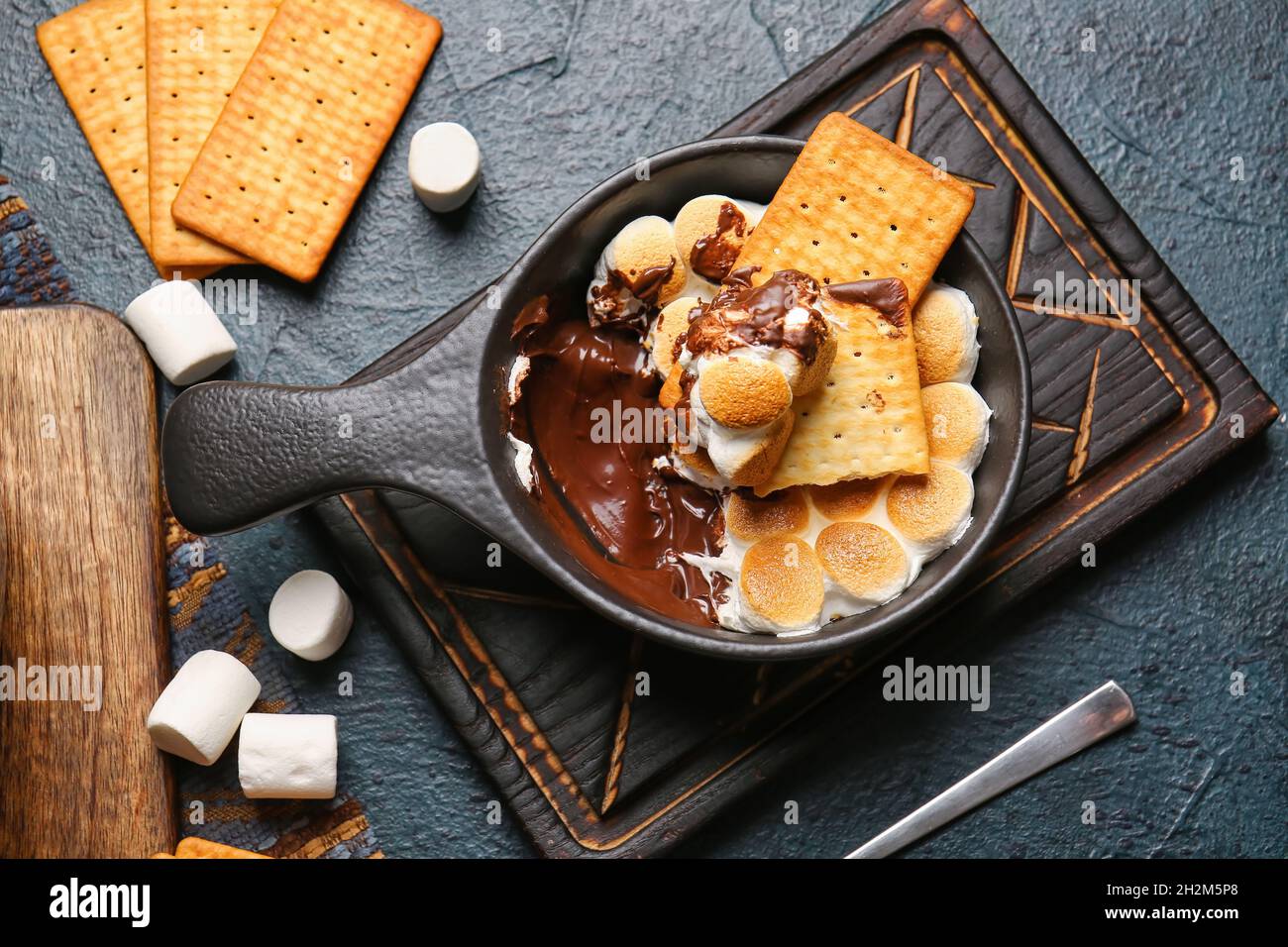 Frying pan with delicious S'mores dip and crackers on dark background ...