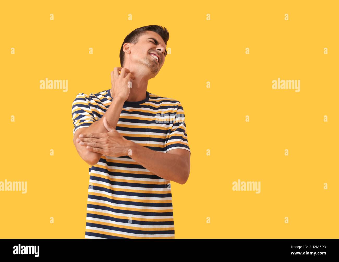 Young man scratching himself on color background Stock Photo - Alamy