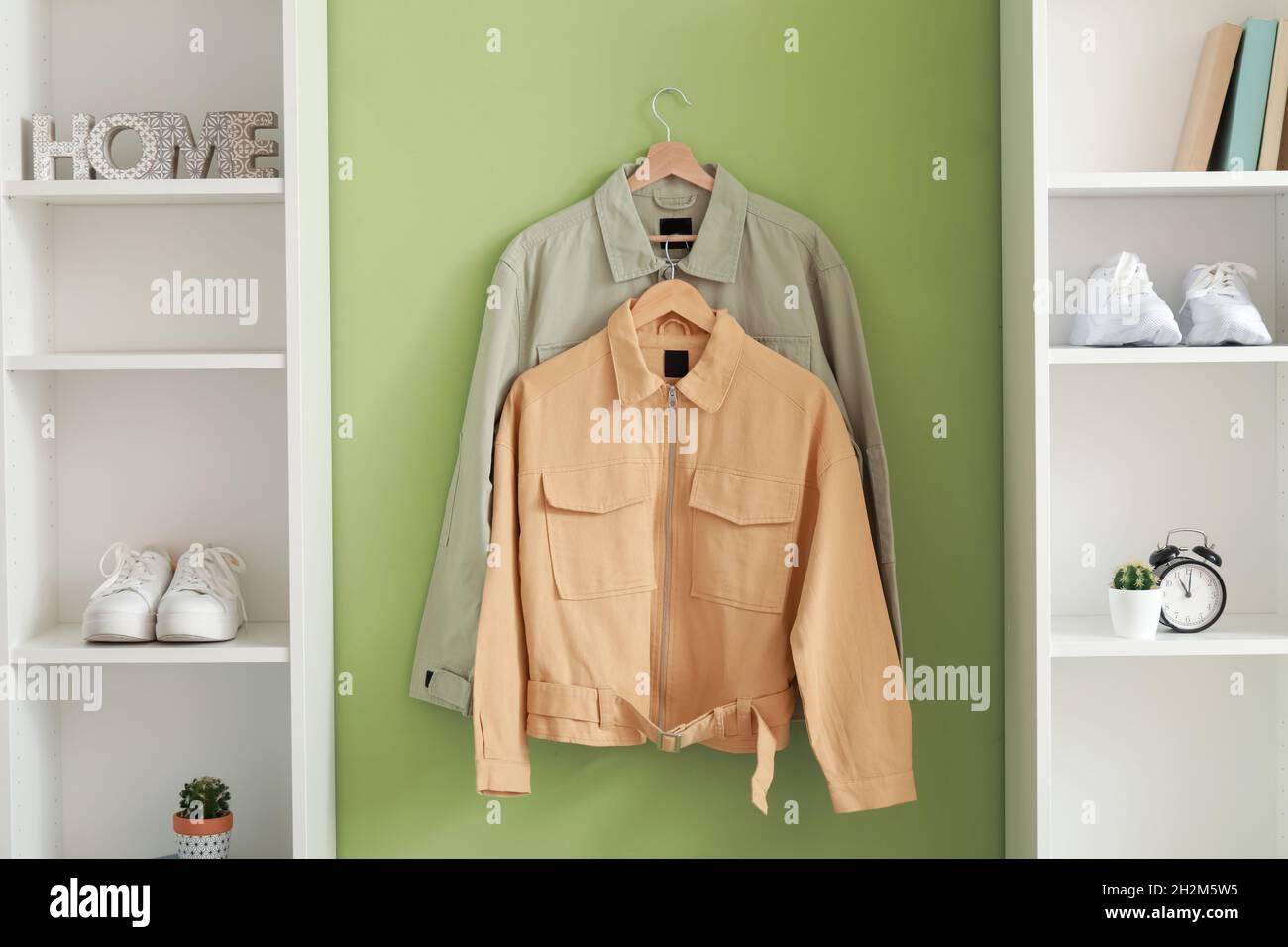 Shelving units and stylish jackets hanging on green wall Stock Photo ...