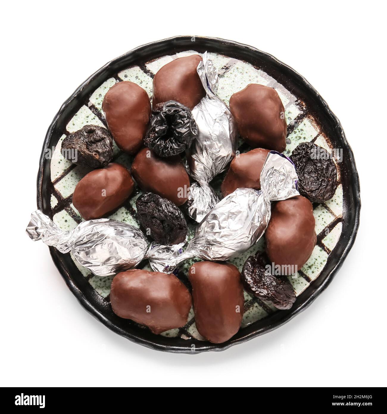 Tray with delicious chocolate candies and prunes on white background ...