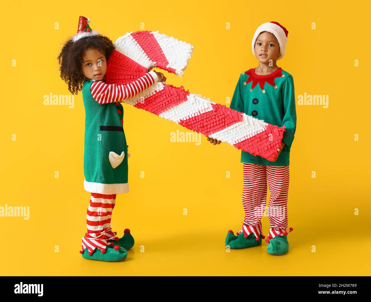 Cute little elves with candy cane pinata on yellow background Stock ...