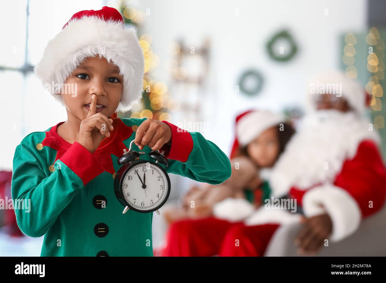 Little African-American boy dressed as elf with alarm clock showing ...