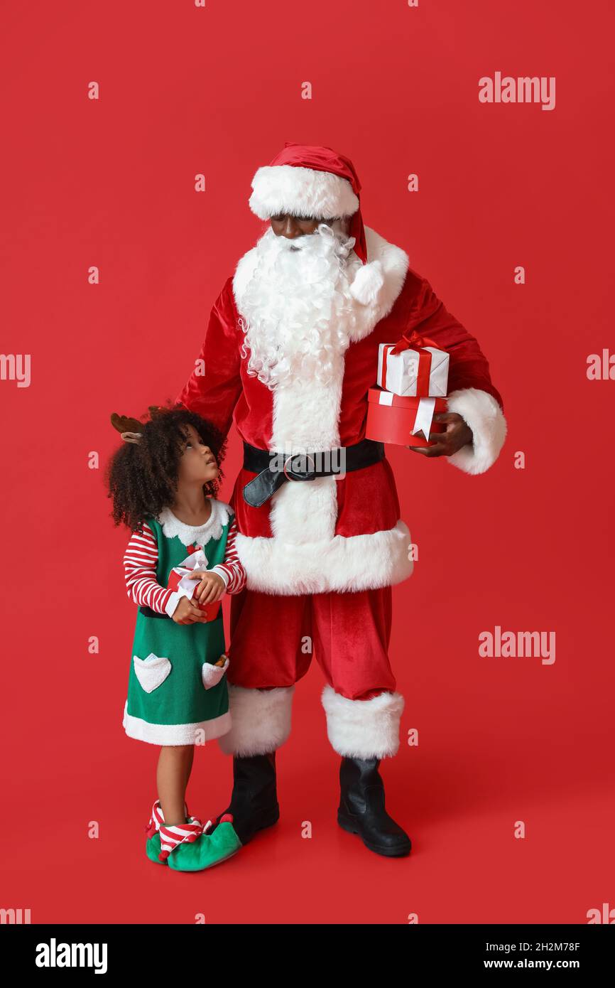 Cute little elf with Santa Claus and gifts on red background Stock ...