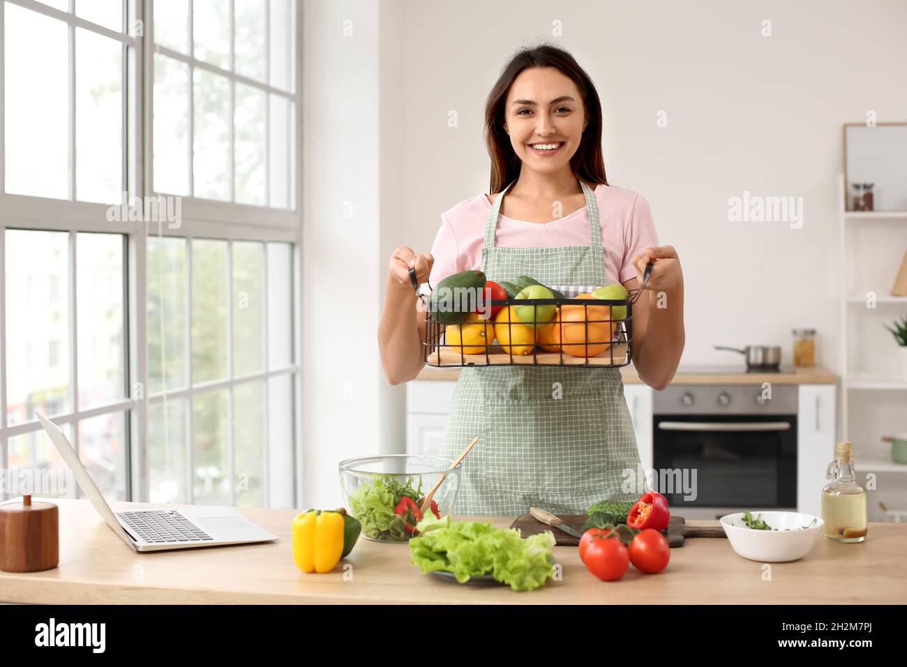 Young woman with fresh vegetables in basket in kitchen Stock Photo - Alamy