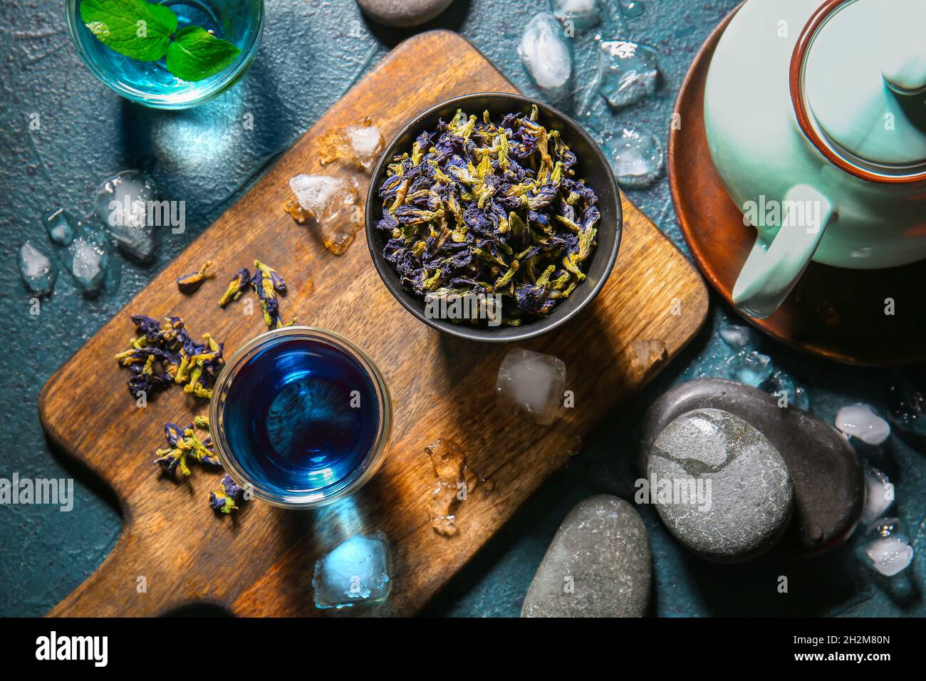 Glass of organic blue tea, dried flowers and ice cubes on dark ...