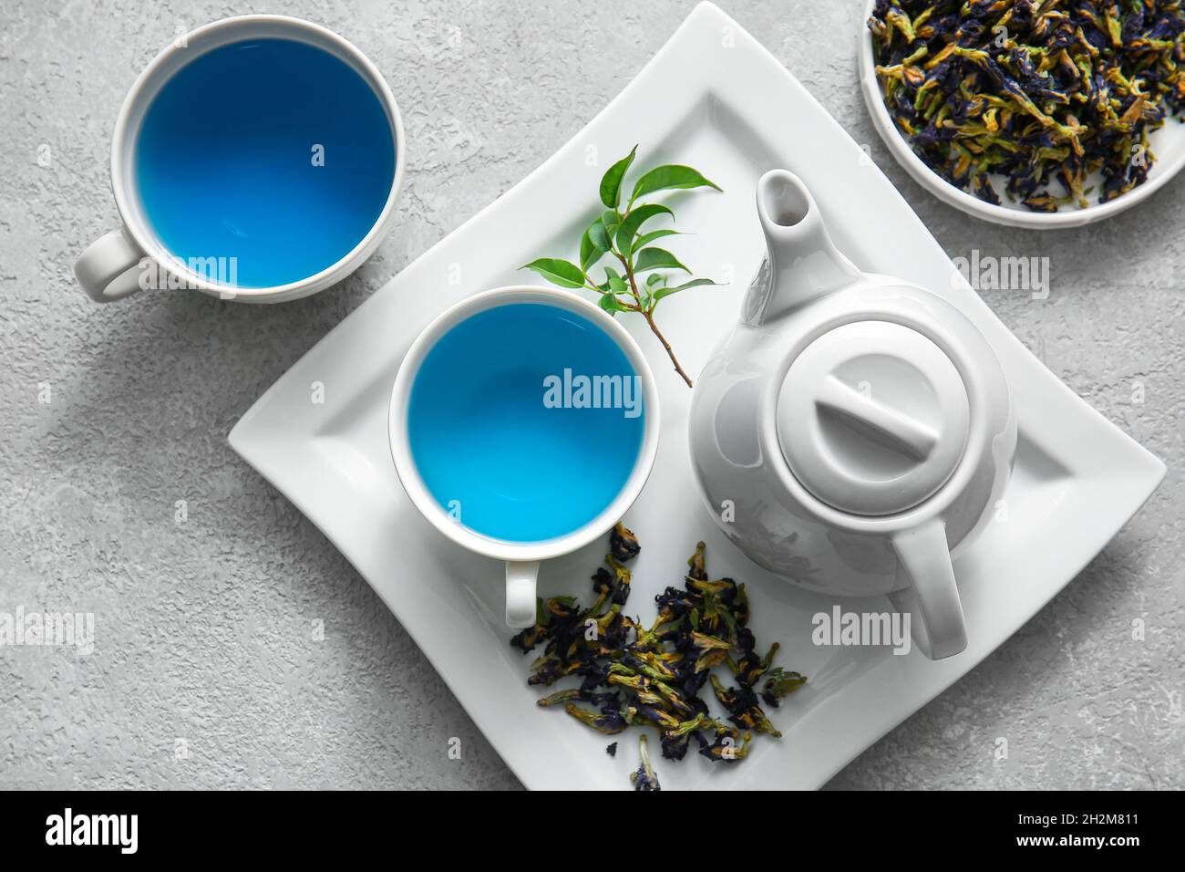 Cups of organic blue tea and dried flowers on light background Stock ...