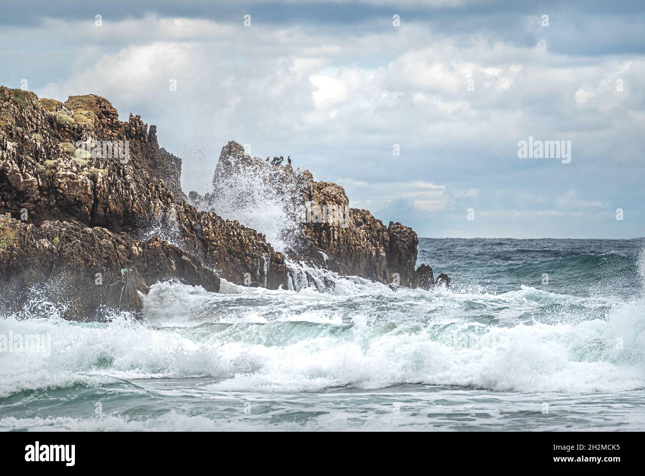 Ocean water splash on rock beach with beautiful sky and clouds. Sea ...
