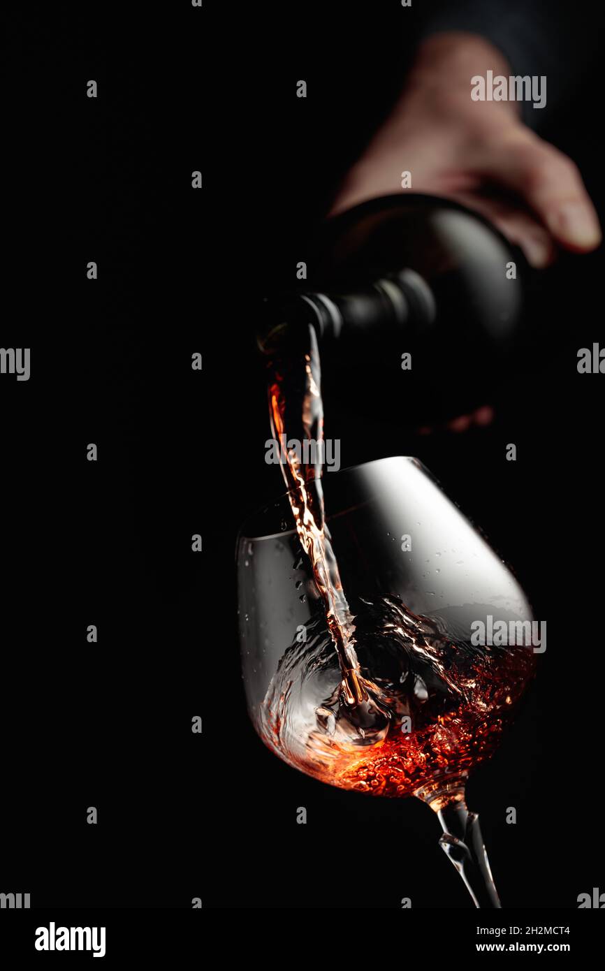 Pouring brandy into a glass. Black background with copy space Stock ...