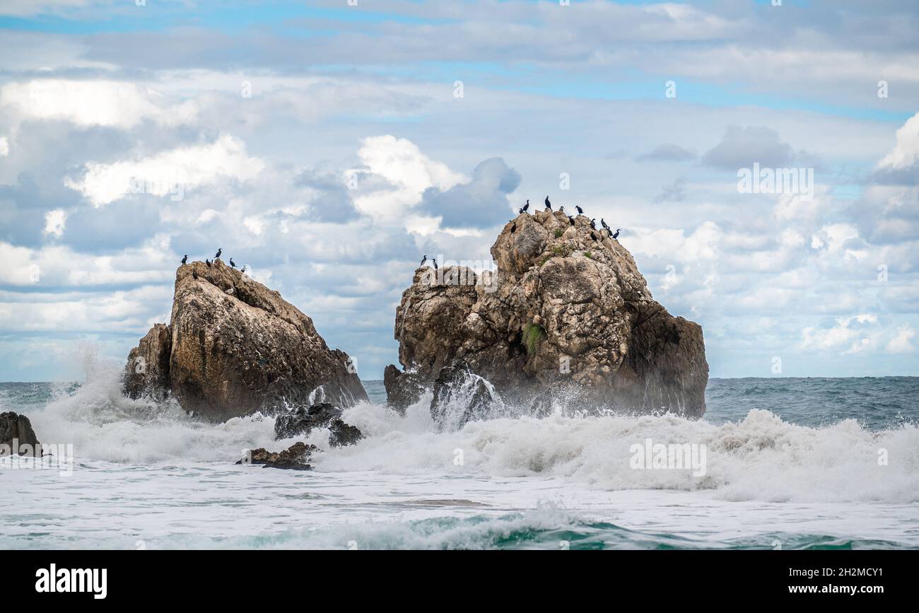Ocean water splash on rock beach with beautiful sky and clouds. Sea ...