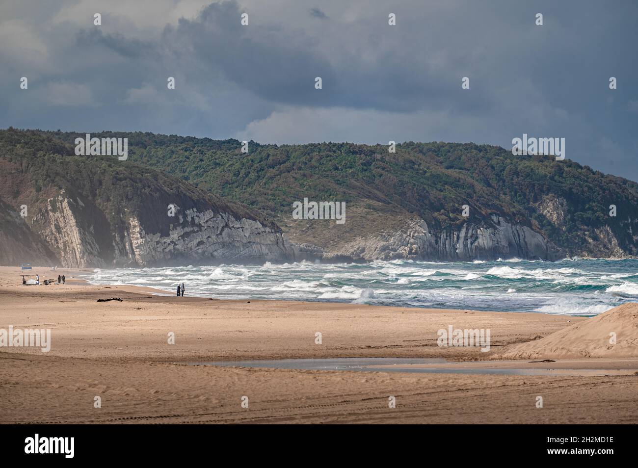 Beautiful sandy ocean beach with large rocks on shore and in the water ...