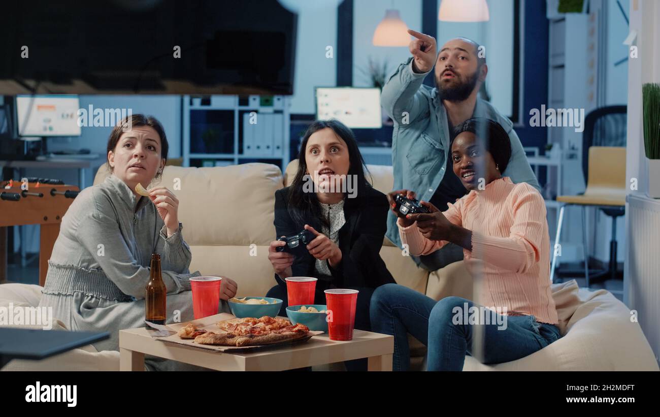 Diverse group of people playing video games on tv console after work ...