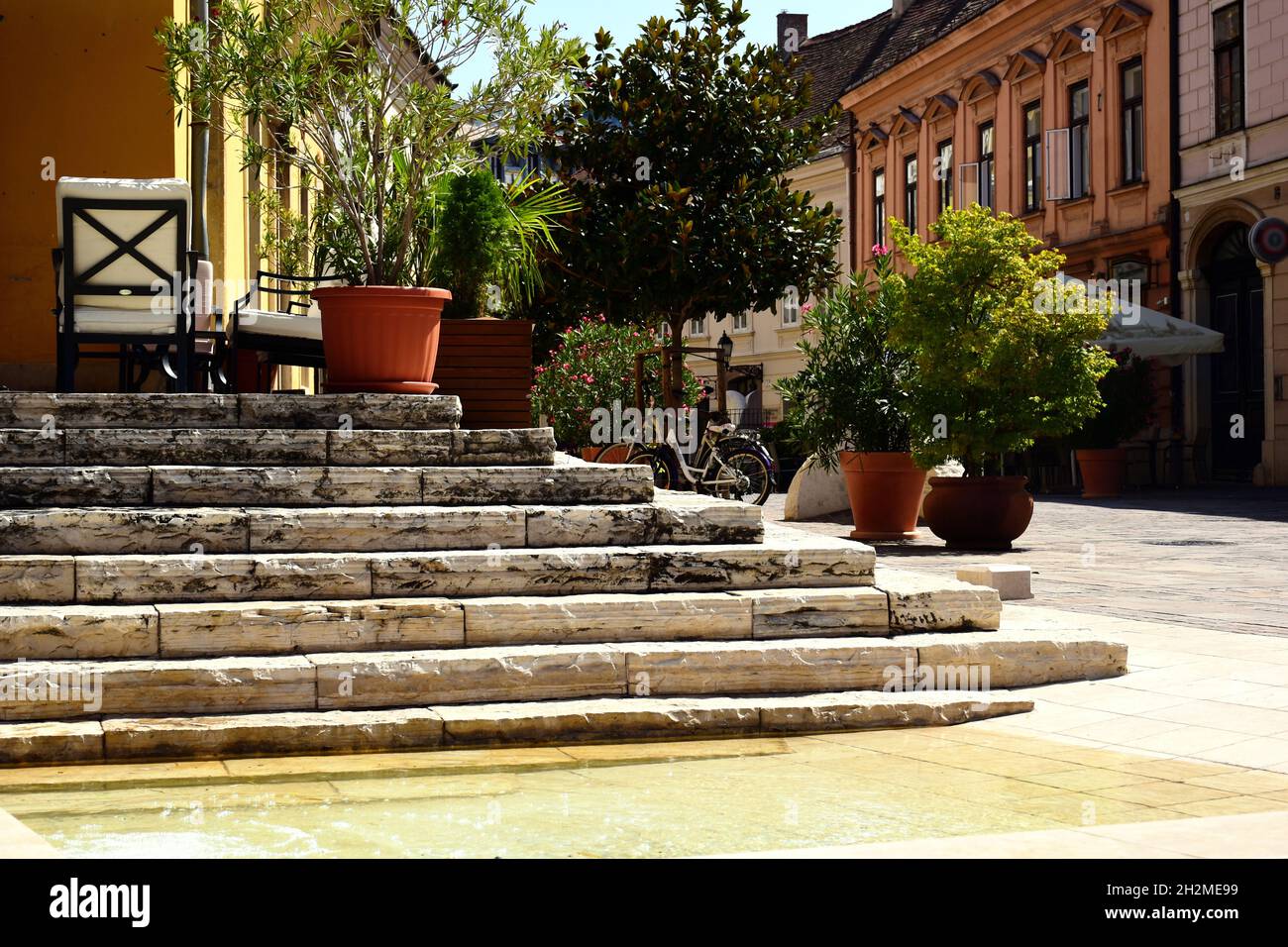 european town square. stone stair, cobblestone pavement, potted green ...
