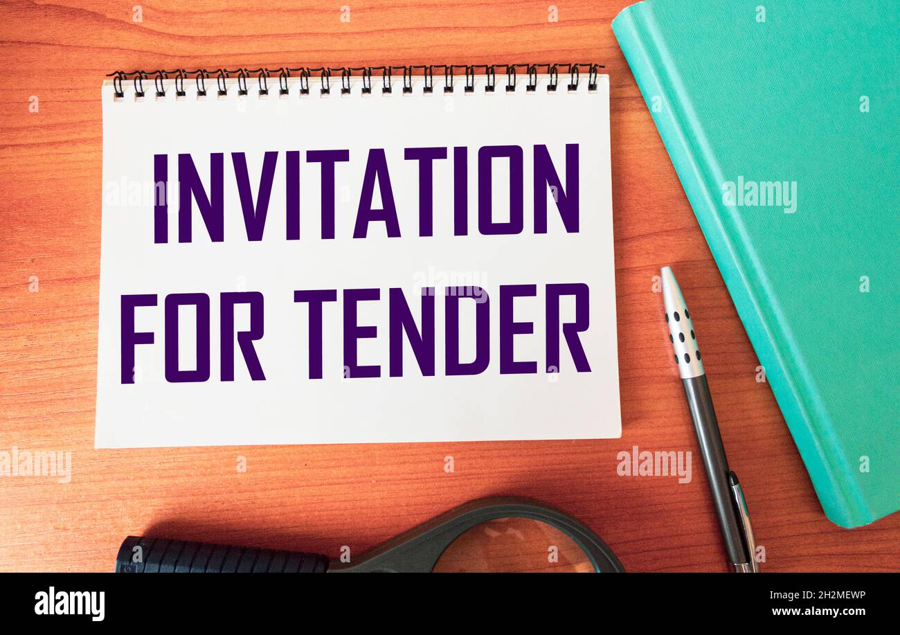 Notepad with the text INVITATION TO TENDER on a wooden background with ...