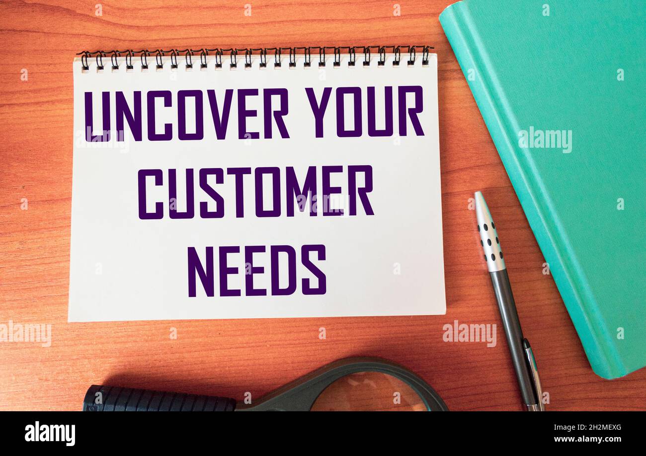 Uncover your customer needs. Wooden background. text on white notepad ...