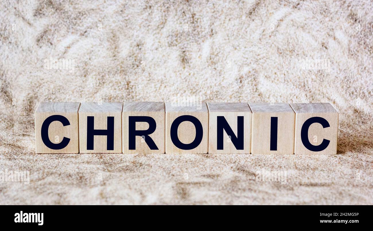 the word Chronic is written on wooden cubes that lie on a sandy ...