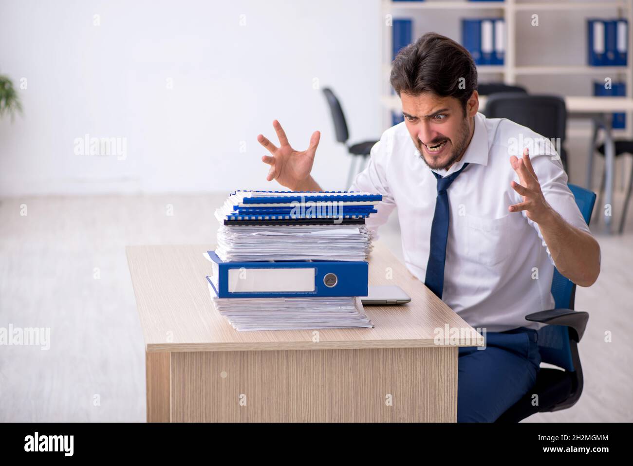 Young businessman employee unhappy with excessive work in the office ...