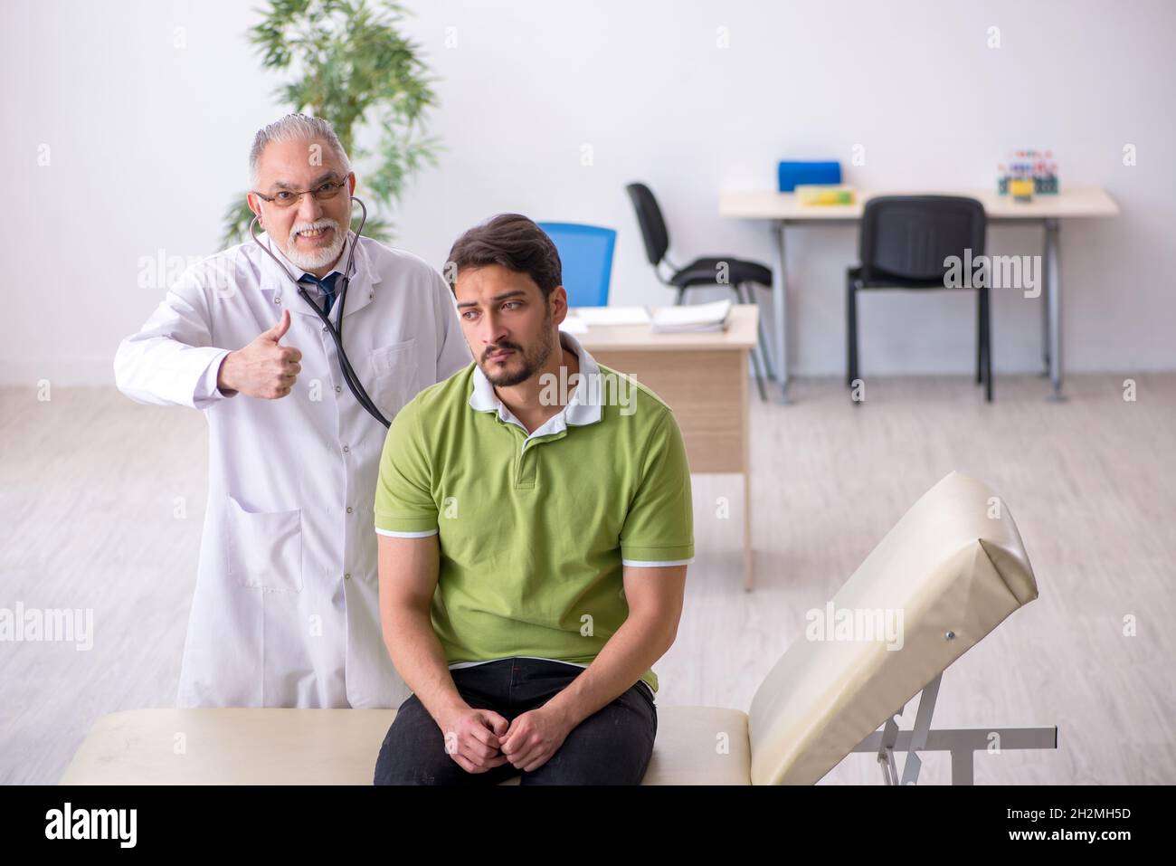 Young man visiting old doctor Stock Photo - Alamy