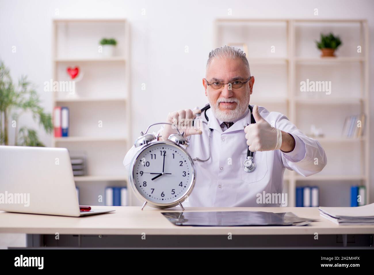Old doctor in time management concept Stock Photo - Alamy