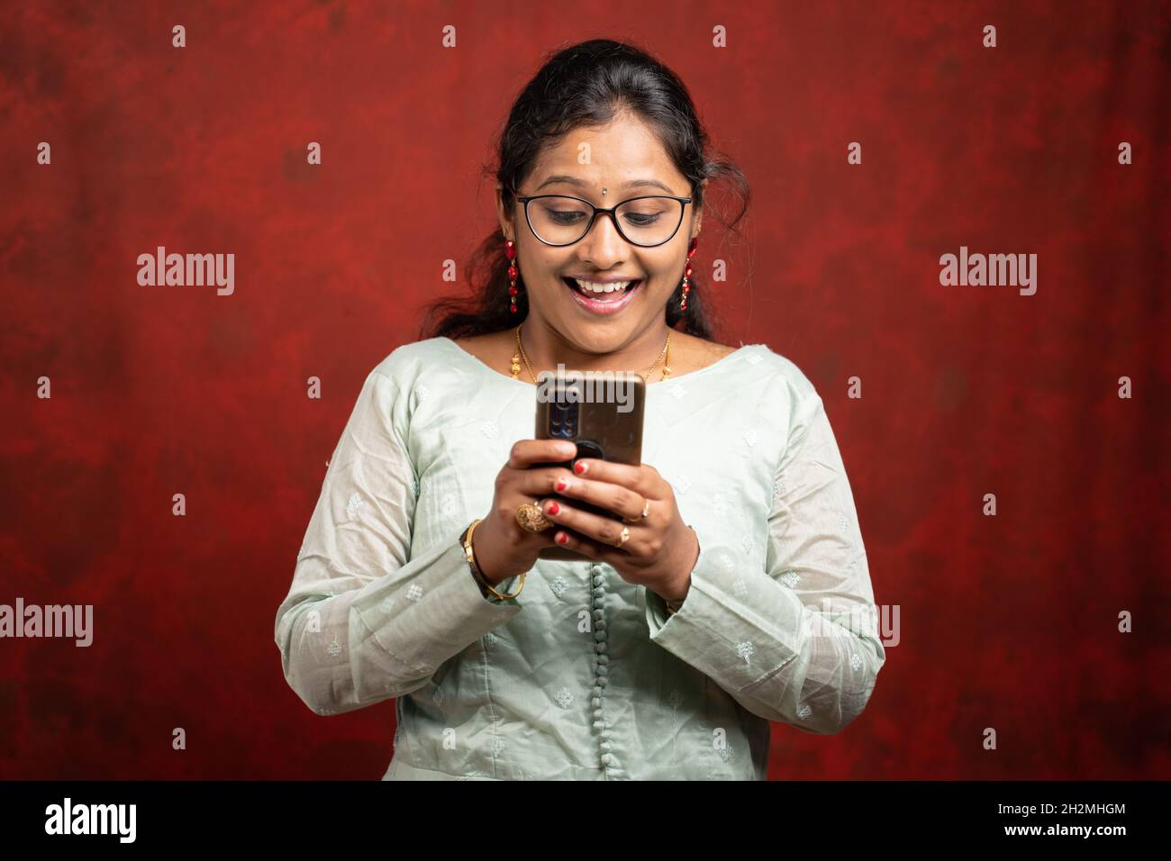 closeup shot of young indian woman surprised while using mobile phone ...