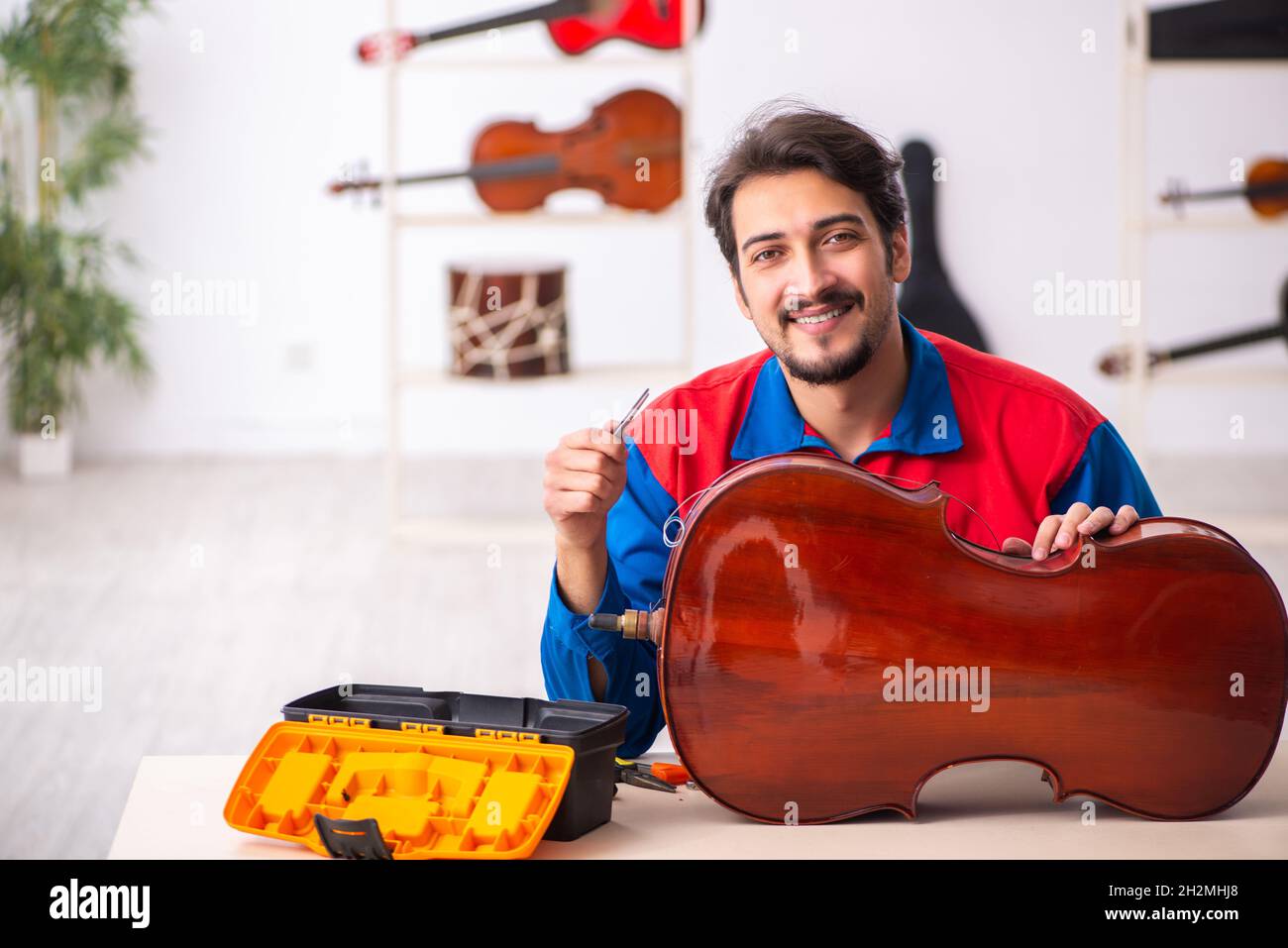 Young repairman repairing musical instruments at workplace Stock Photo ...