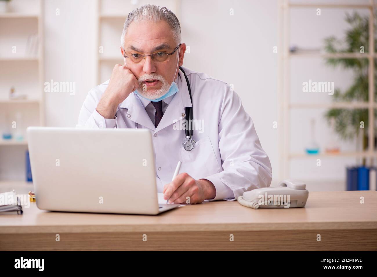 Old doctor working in the clinic during pandemic Stock Photo - Alamy