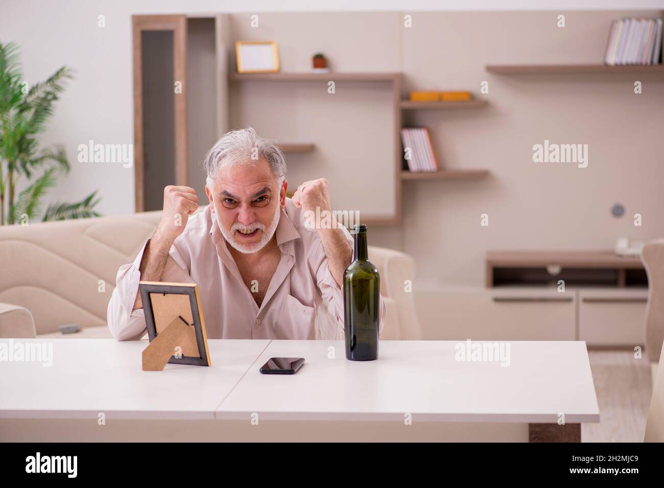 Aged widower drinking alcohol at home Stock Photo - Alamy
