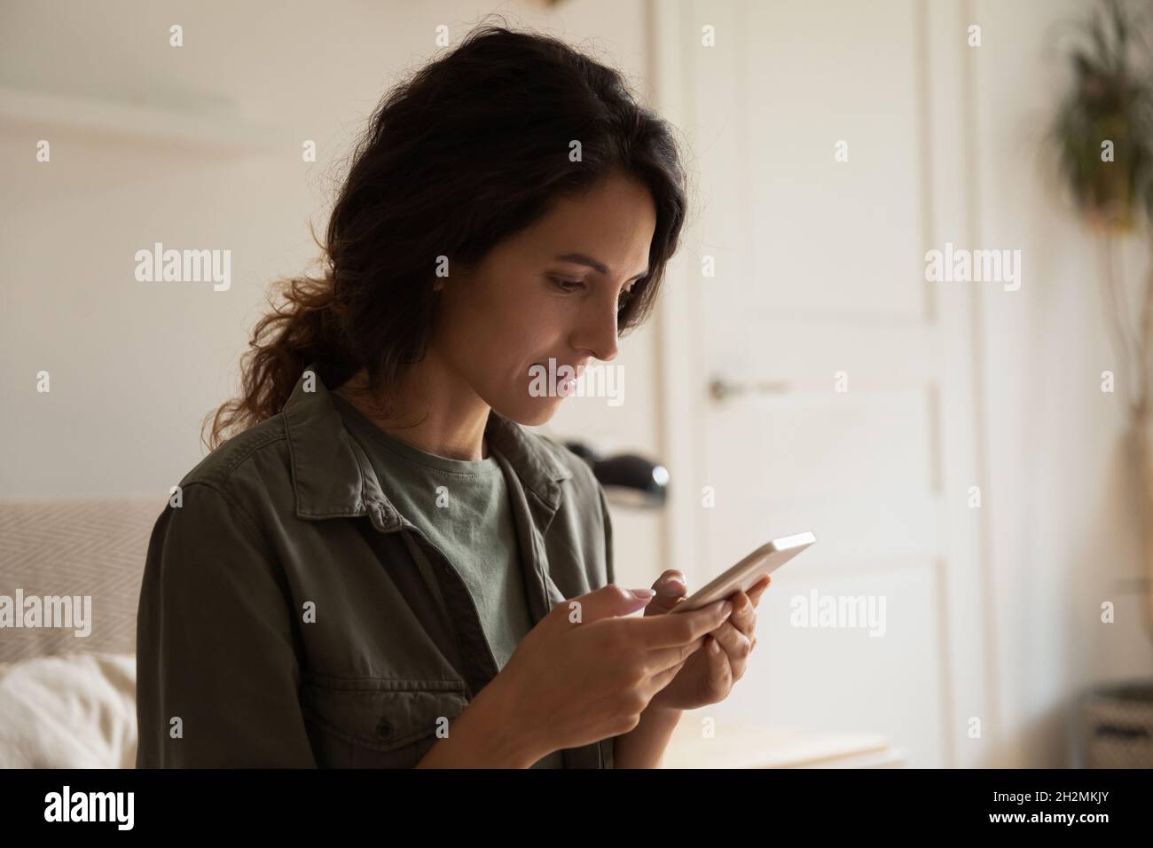 Focused positive cellphone user texting message, using app on ...