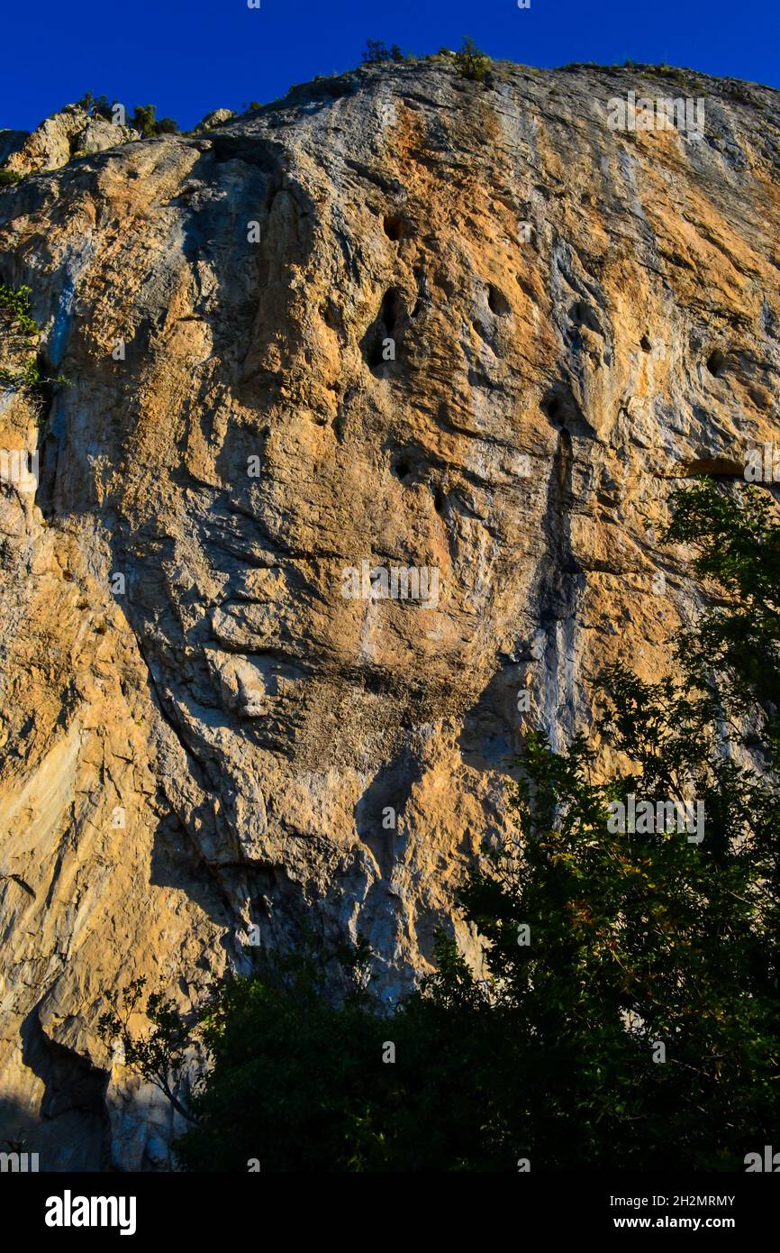 Dangerous and steep high sheer cliff with burrows of birds and ...