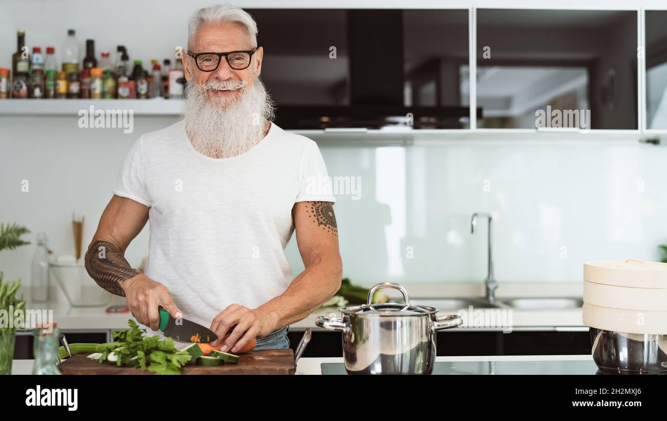 Happy senior man having fun cooking at home - Elderly person preparing ...