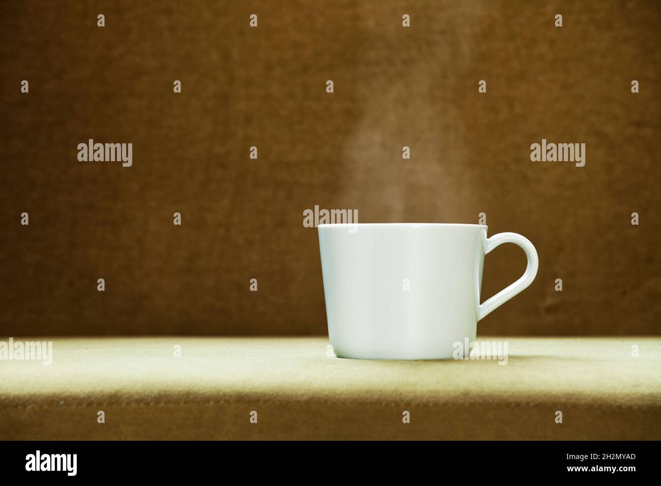 White ceramic mug on coffee table with hot steaming beverage inside ...