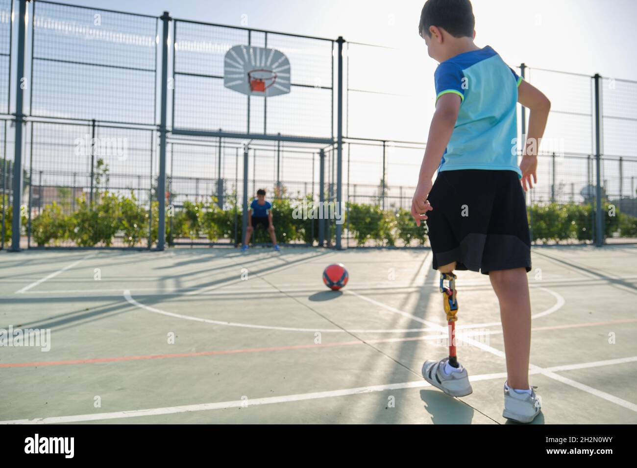Two friends playing football, one has a leg prosthesis and is kicking a ...