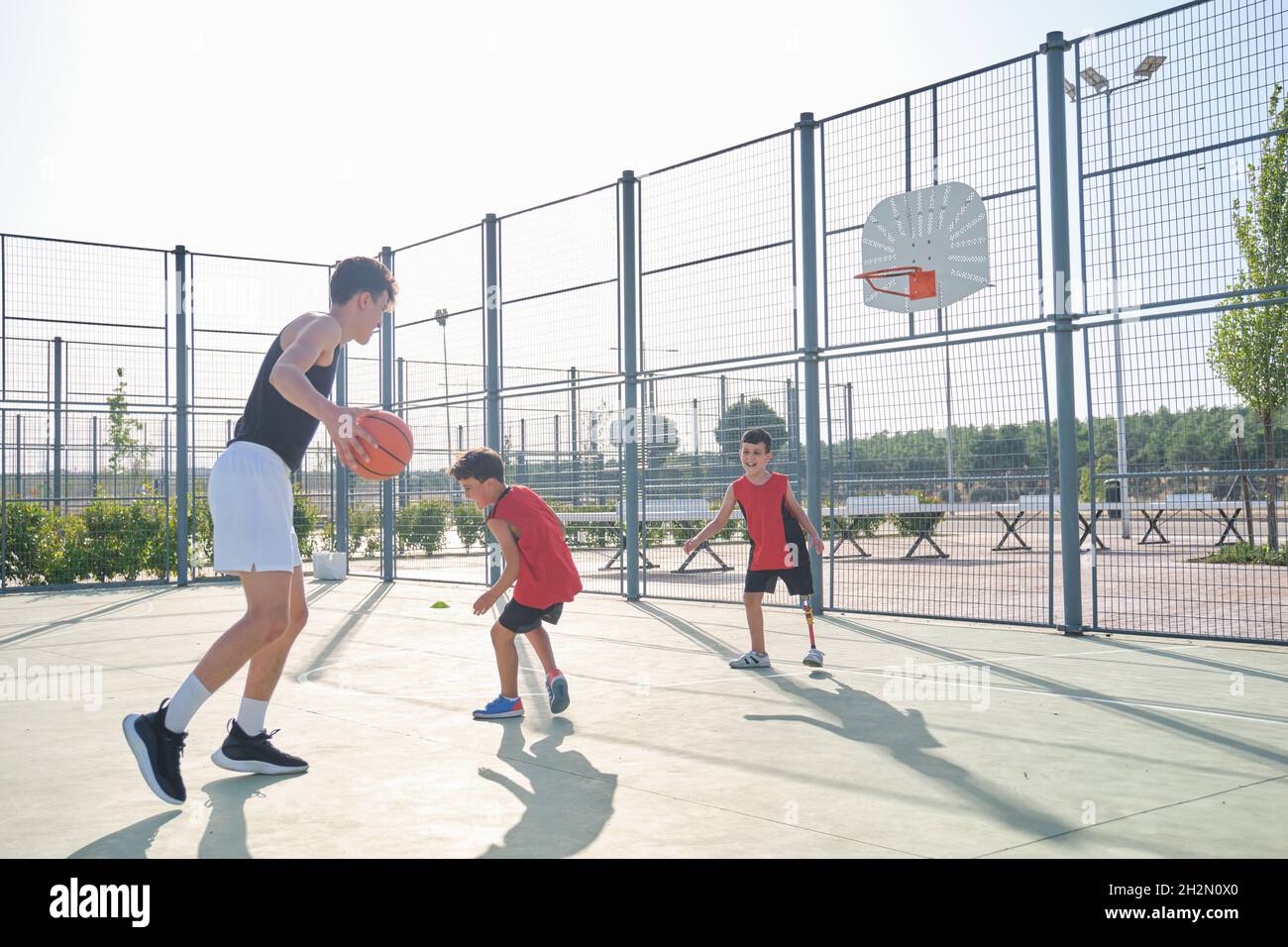 Basketball trainer play basketball with two children, one has a leg ...