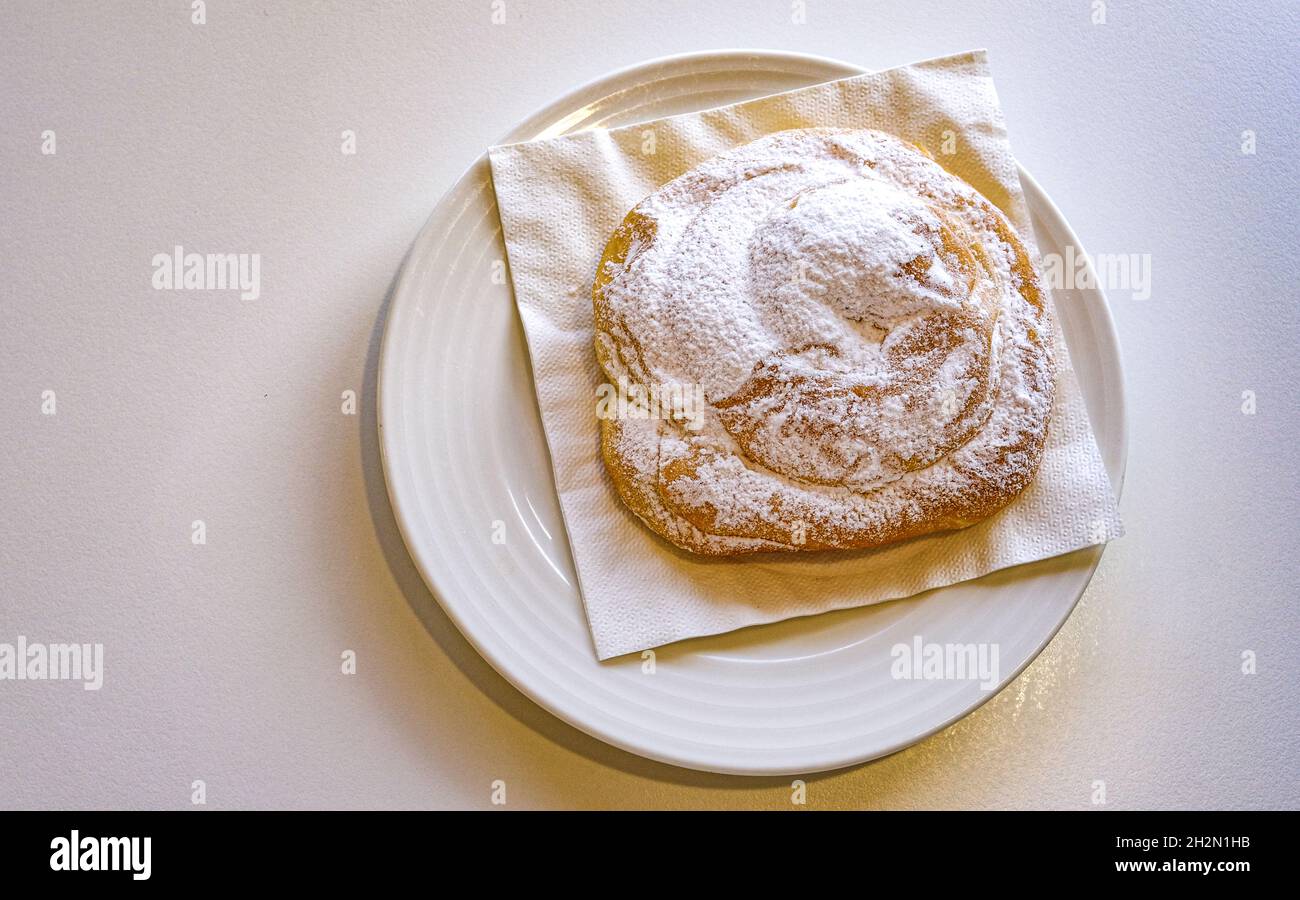 typical dessert of Menorca: ensaimada. on white plate and white table ...