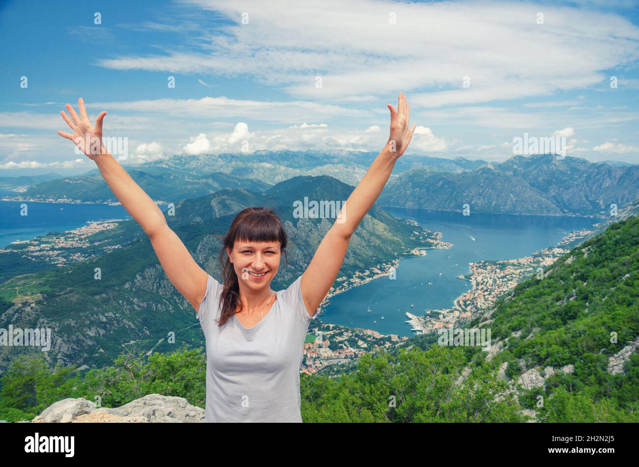 Young beautiful girl traveler with grey t-shirt raise hands and smile ...