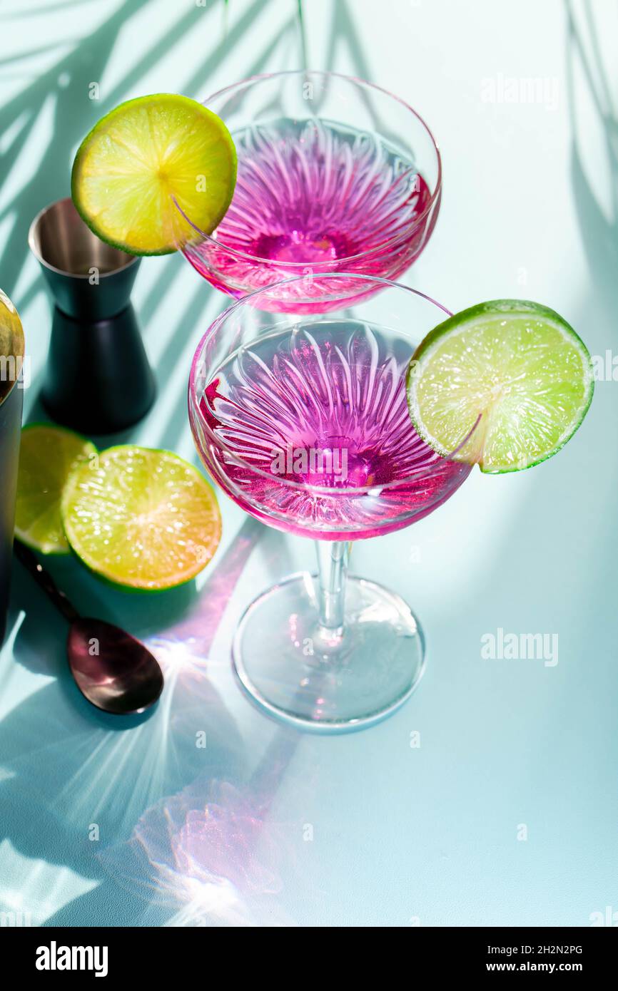 A pair of cocktail glasses with campari decorated with lime slices ...