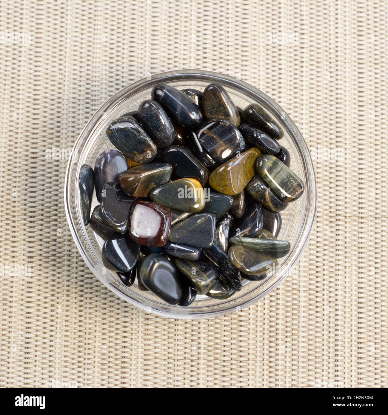 Smooth piece of hawk eye natural mineral macro on grey background ...