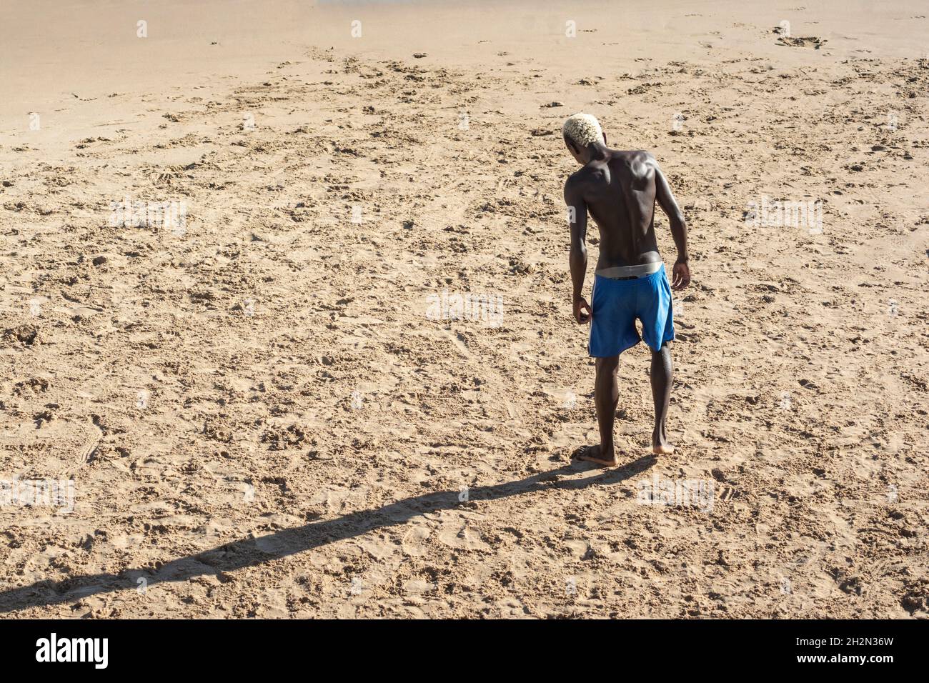 Young model playing sand football on the beach under strong summer sun ...