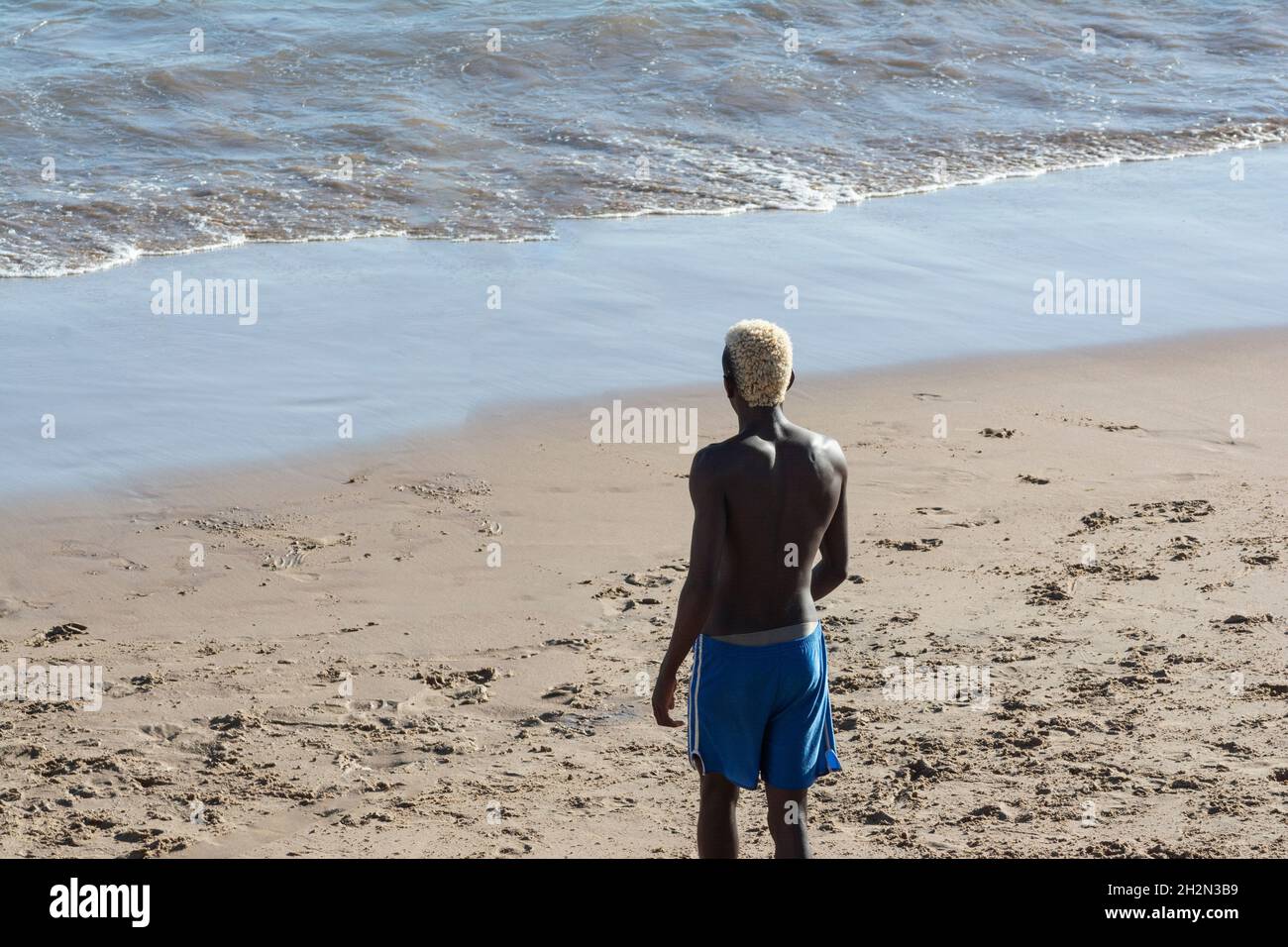 Young model playing sand football on the beach under strong summer sun ...
