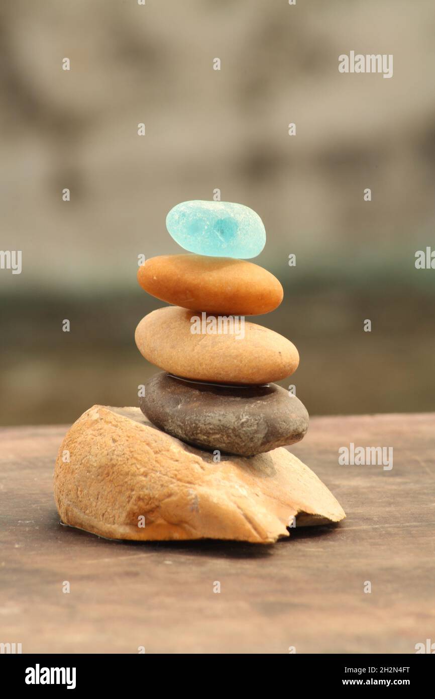 Different types of stone pebbles and sea glass balances on a wood plank ...