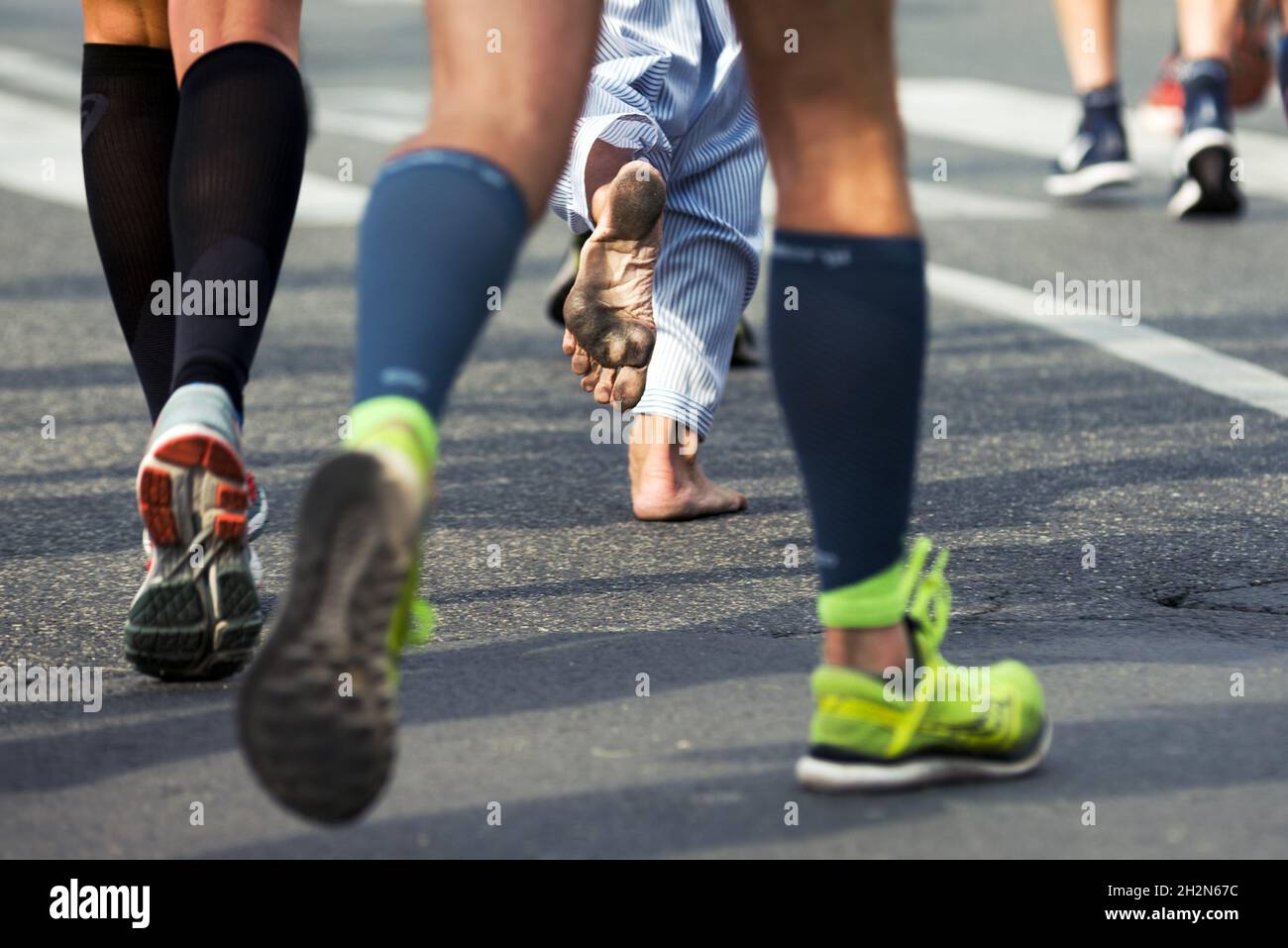 Barefoot runner foot among shoved runners legs in Marathon Stock Photo ...