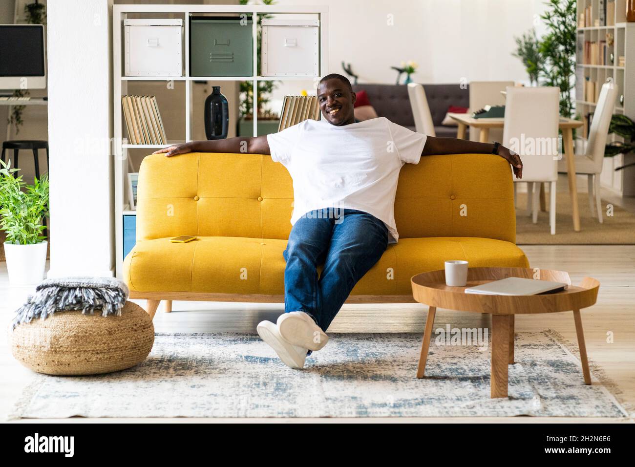 Man sitting on sofa at home Stock Photo - Alamy
