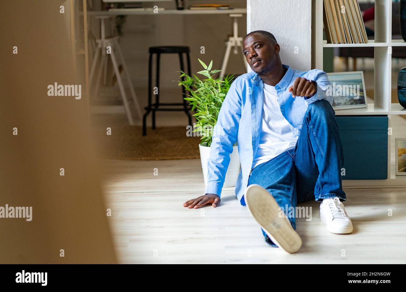 Smiling man sitting in front of column at home Stock Photo - Alamy