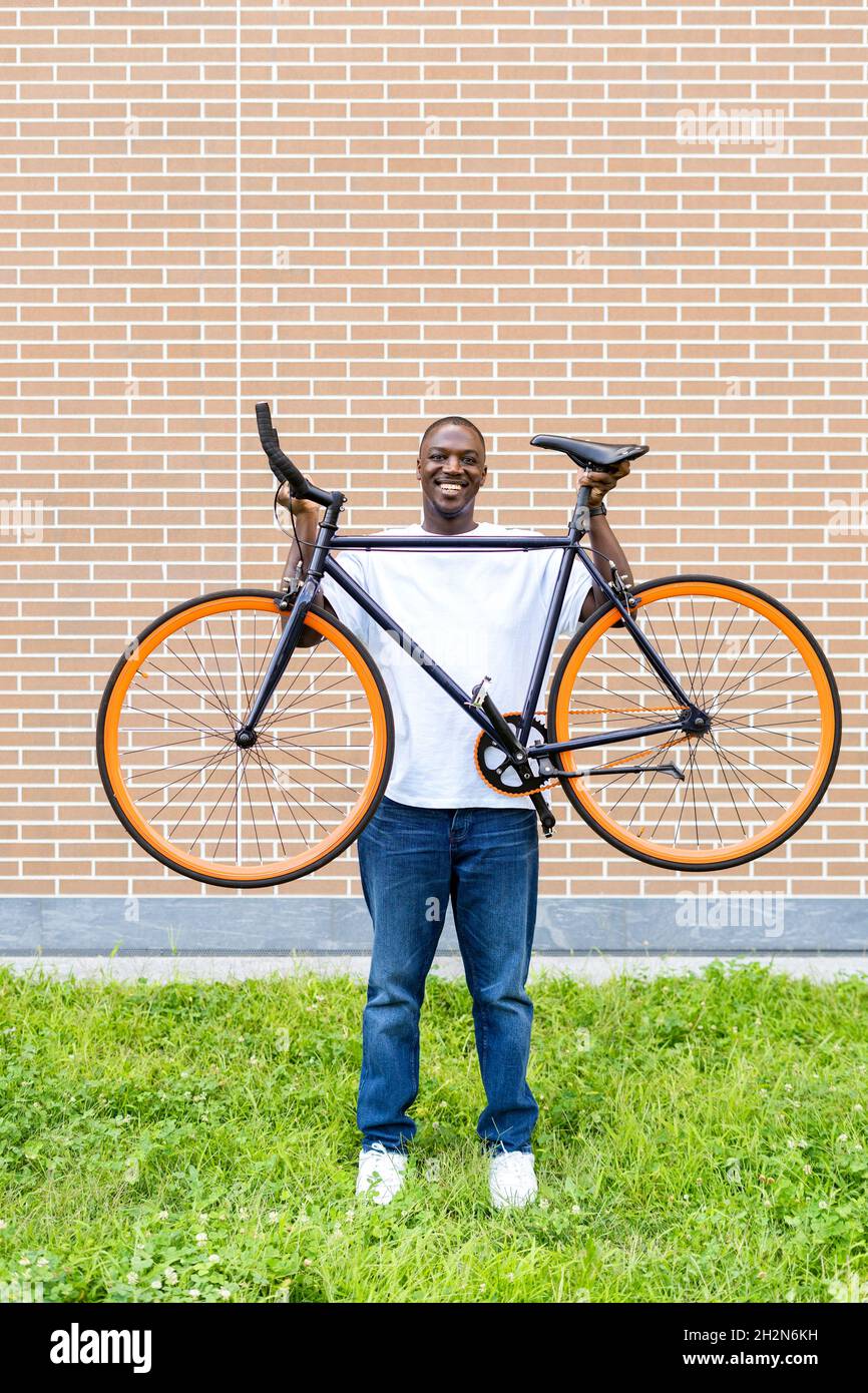 Man wheeling bicycle in front of brick wall Stock Photo - Alamy