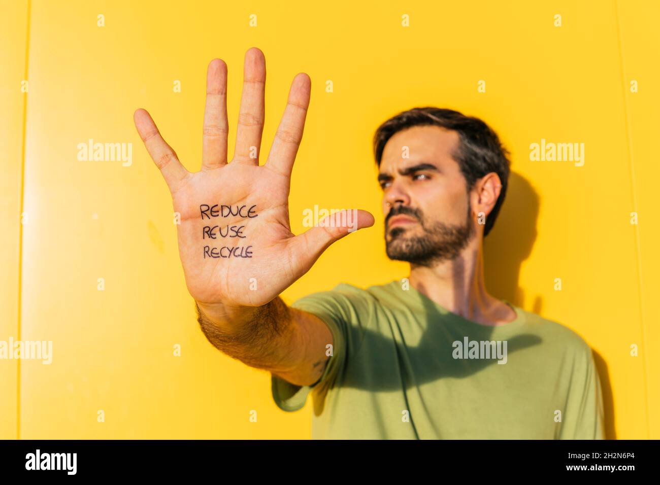 Young man with message written on palm standing in front of yellow wall ...