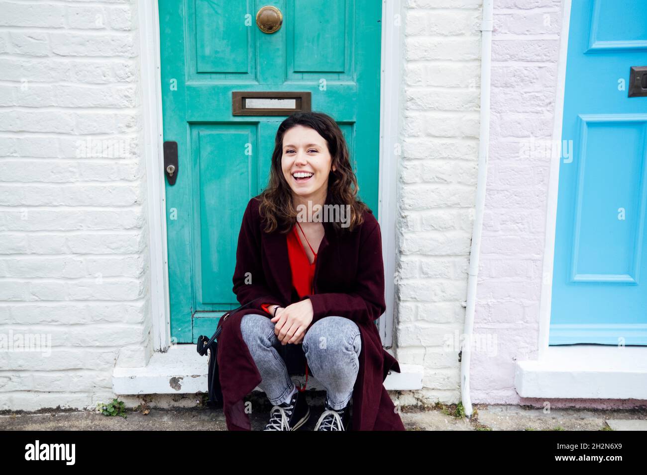 Cheerful young woman sitting on doorstep Stock Photo - Alamy