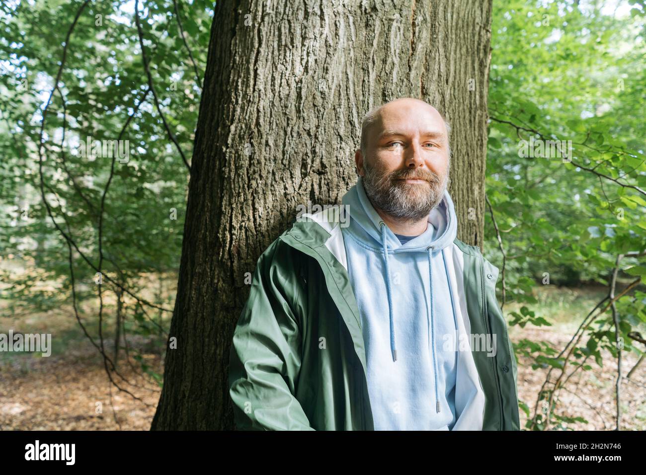 Bearded man standing in front of tree Stock Photo - Alamy