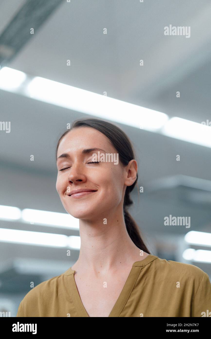 Smiling businesswoman with eyes closed in industry Stock Photo - Alamy