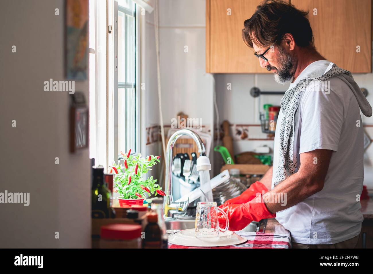 Bearded man cleaning utensils at sink in kitchen Stock Photo - Alamy